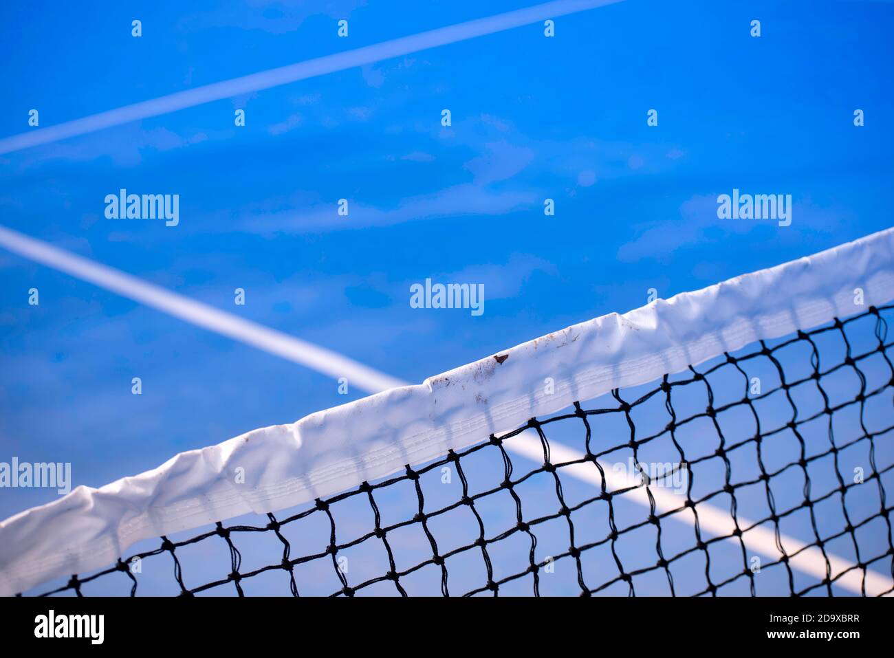 Tennis court net in sports venue with blue playing surface. A view ...
