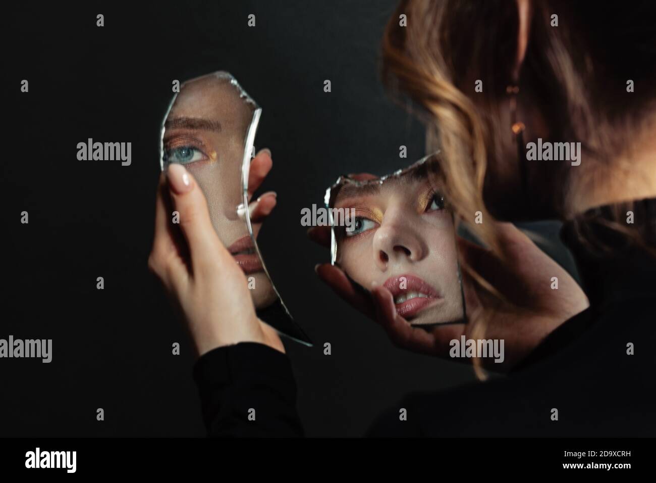 Perfect woman looking at broken self-image mirror on black background ...