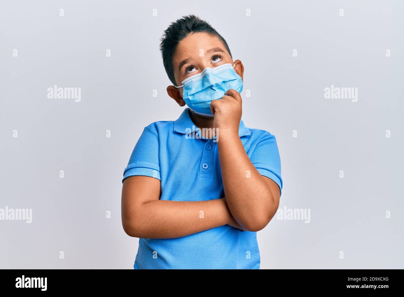 Little boy hispanic kid wearing medical mask thinking concentrated ...
