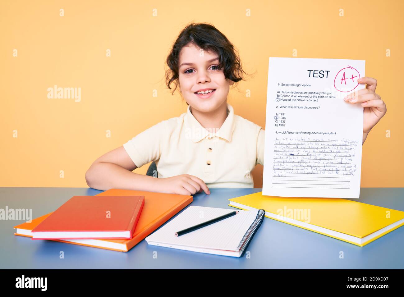Cute hispanic child showing a passed exam sitting on the desk looking ...