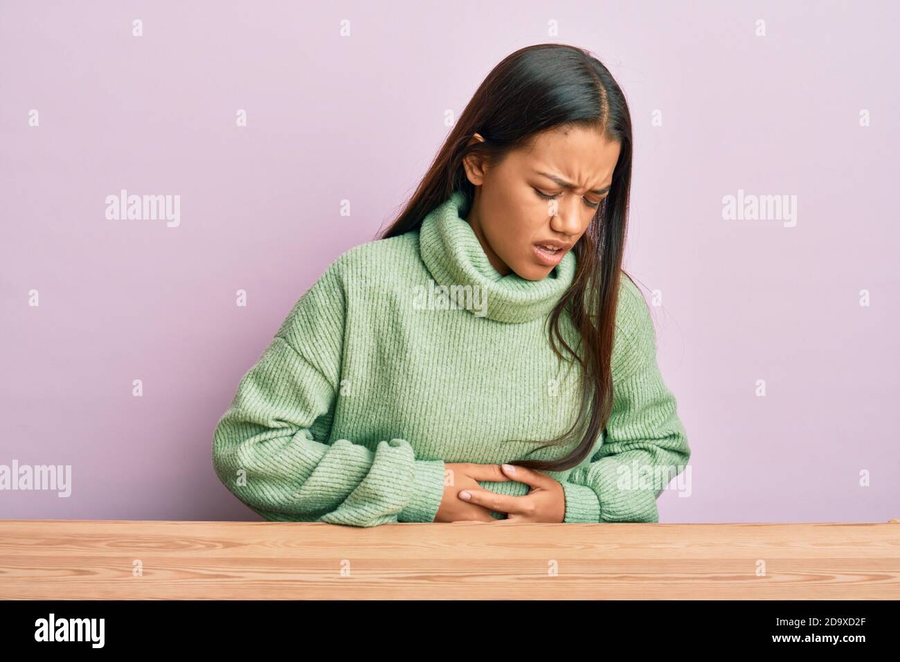 Beautiful hispanic woman wearing casual clothes sitting on the table ...