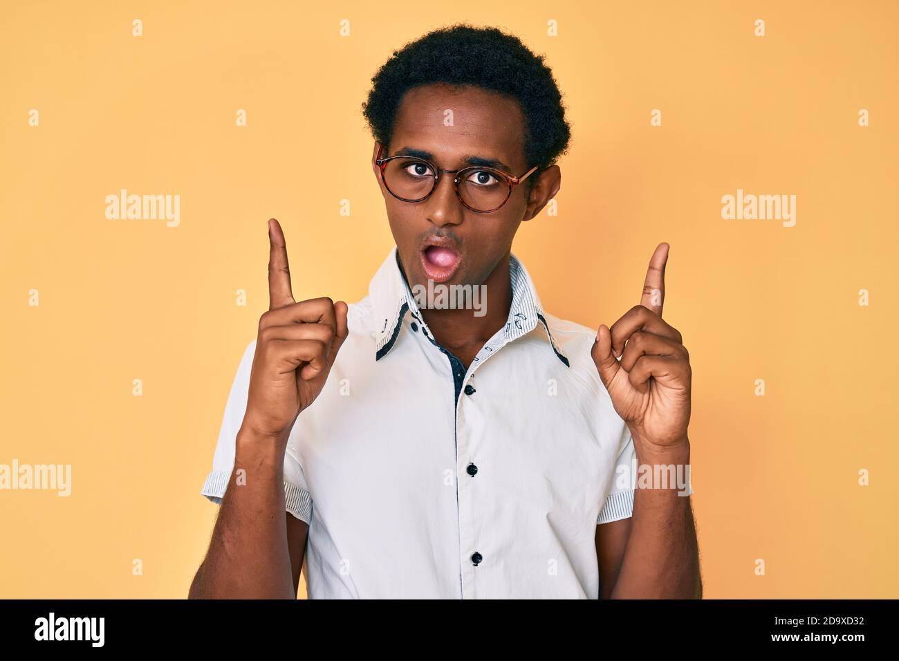 African handsome man pointing up with fingers in shock face, looking ...