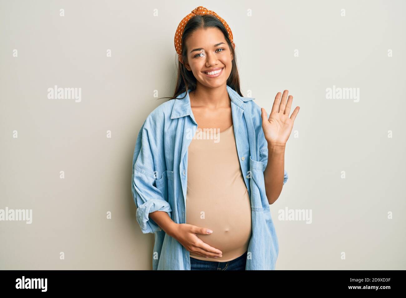 Beautiful hispanic woman expecting a baby, touching pregnant belly ...