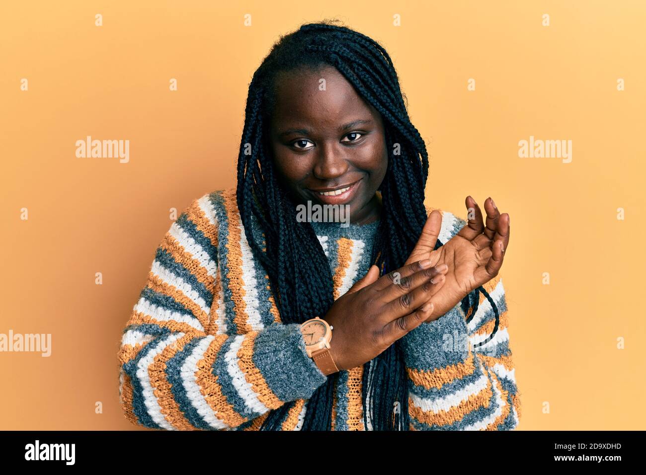 Young black woman with braids wearing casual winter sweater clapping ...