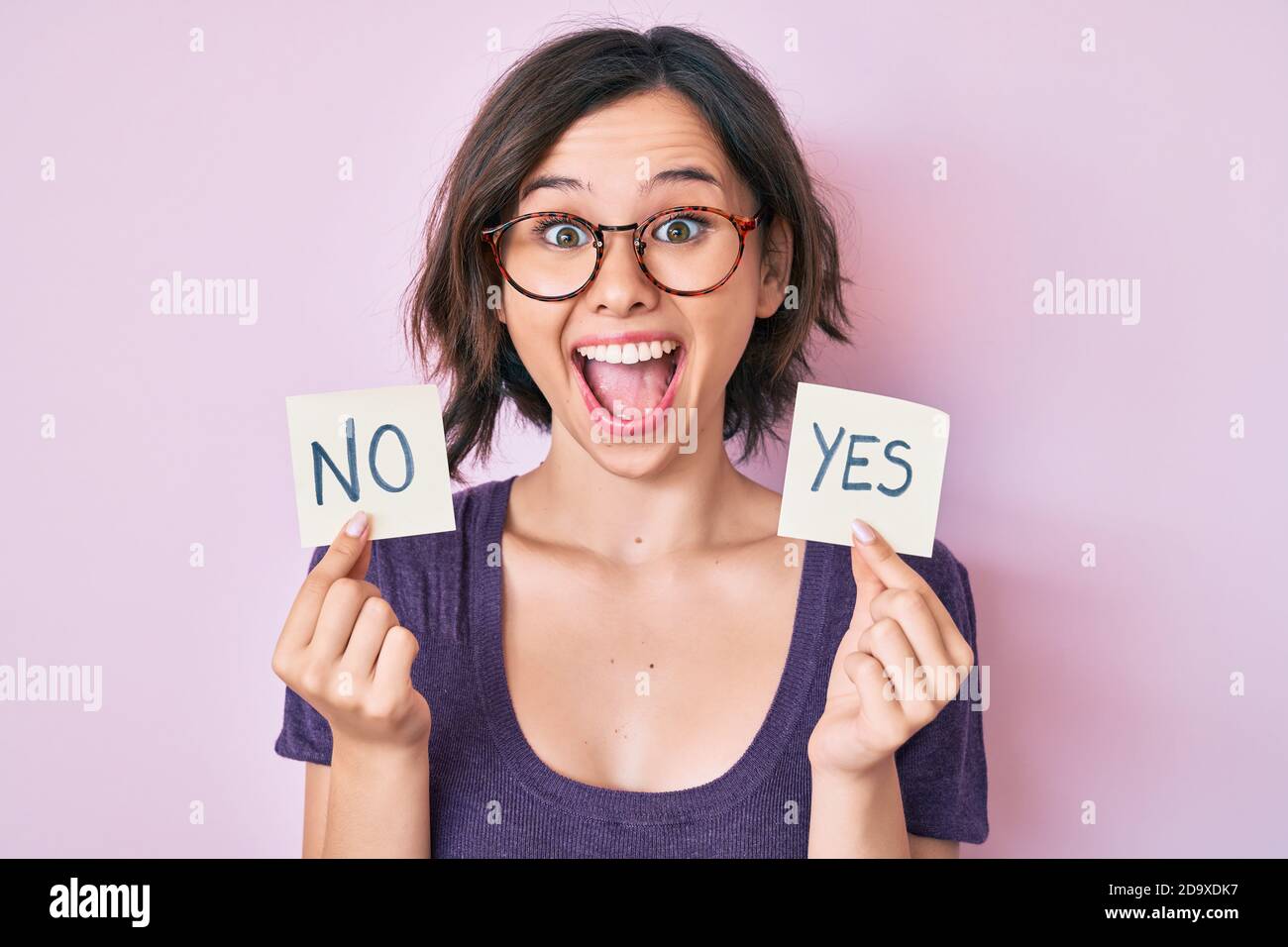 Young beautiful girl holding yes and no reminder celebrating crazy and ...