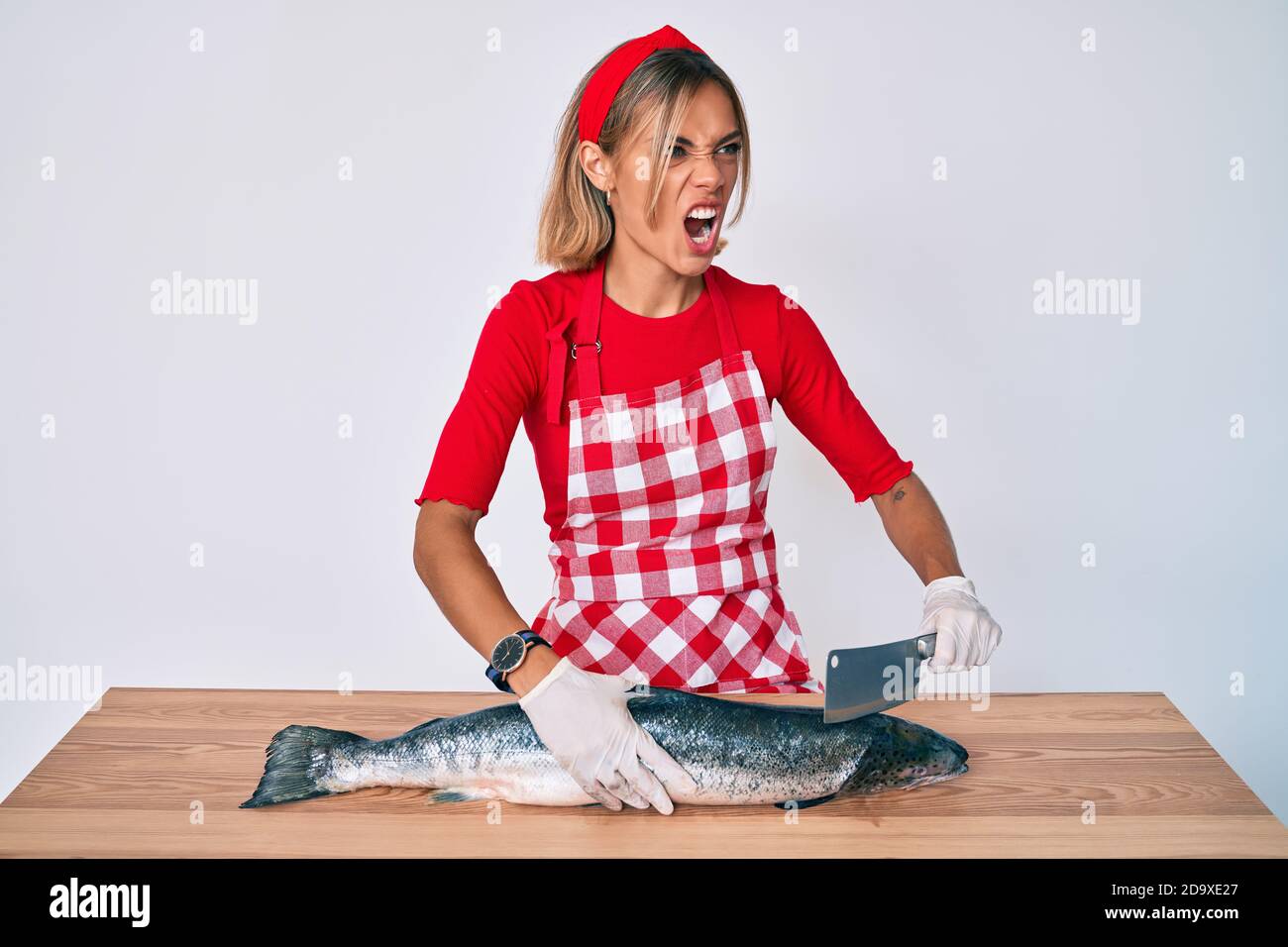 Beautiful caucasian woman fishmonger selling fresh raw salmon angry and ...