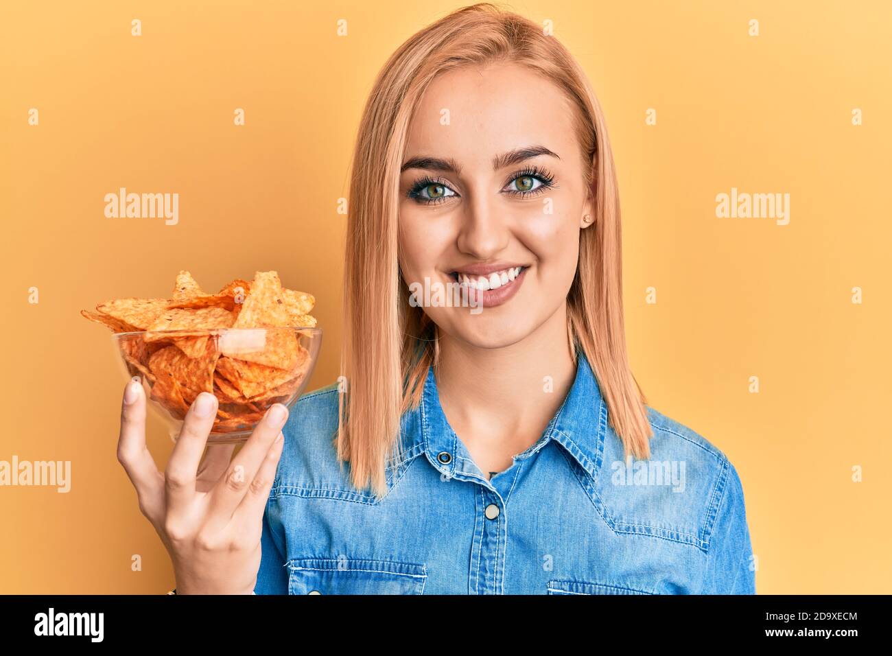 Beautiful caucasian woman holding nachos potato chips looking positive ...