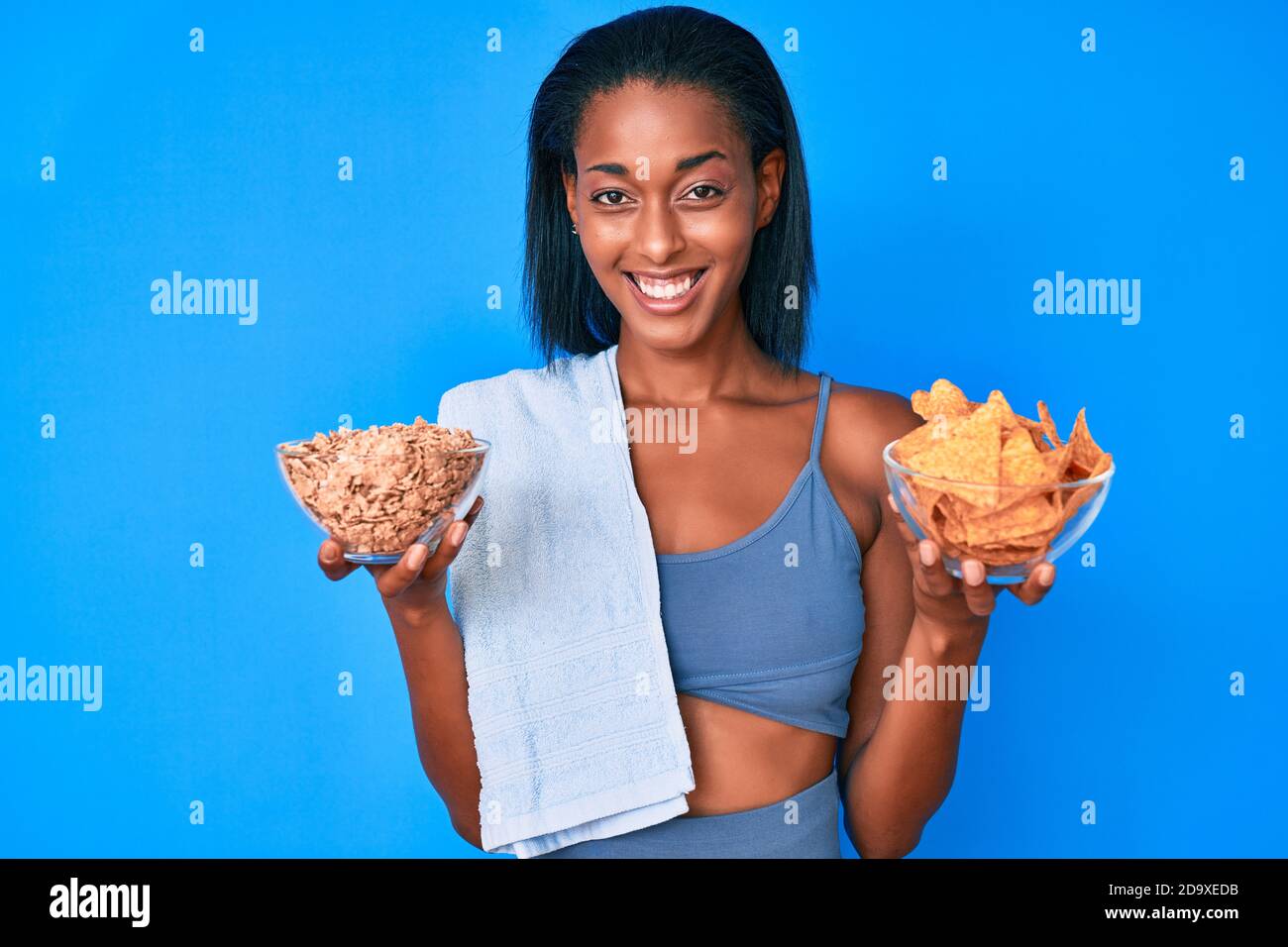 Young african american woman wearing sportswear holding nachos and ...