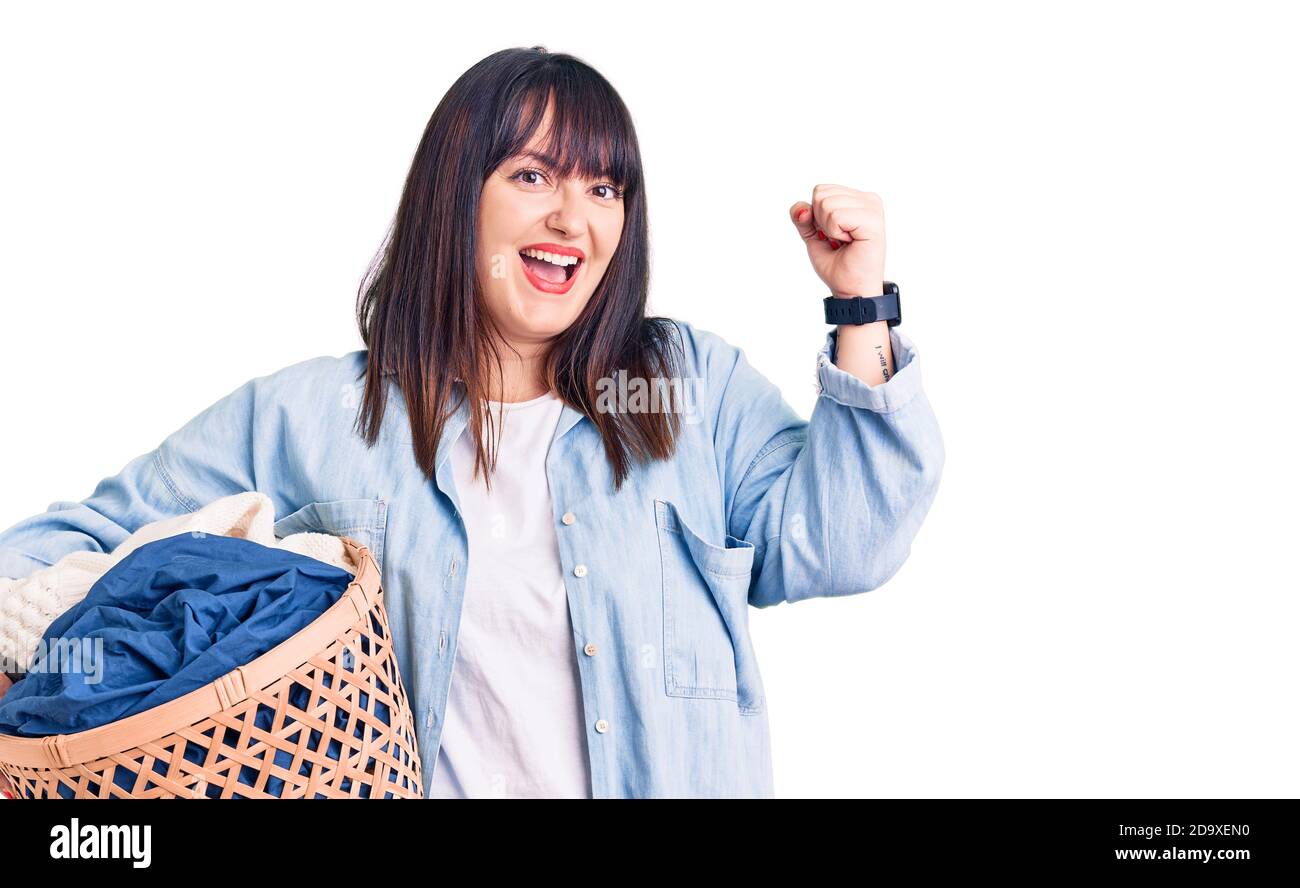 Young plus size woman holding laundry basket screaming proud ...