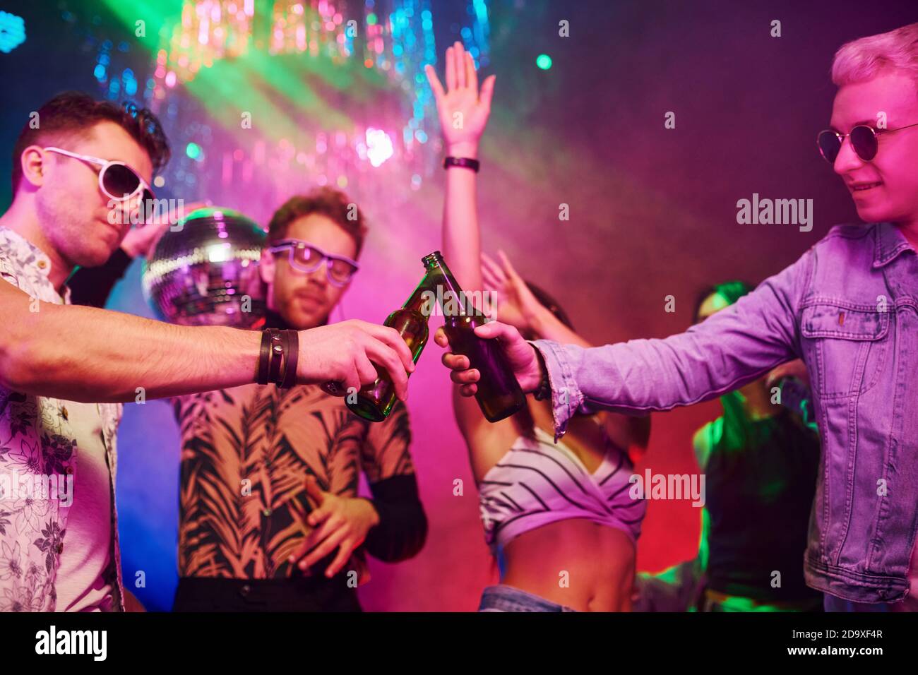 Celebrating and knocking bottles with alcohol. Young people is having ...