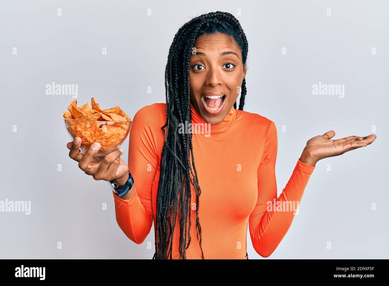 African american woman holding nachos potato chips celebrating ...