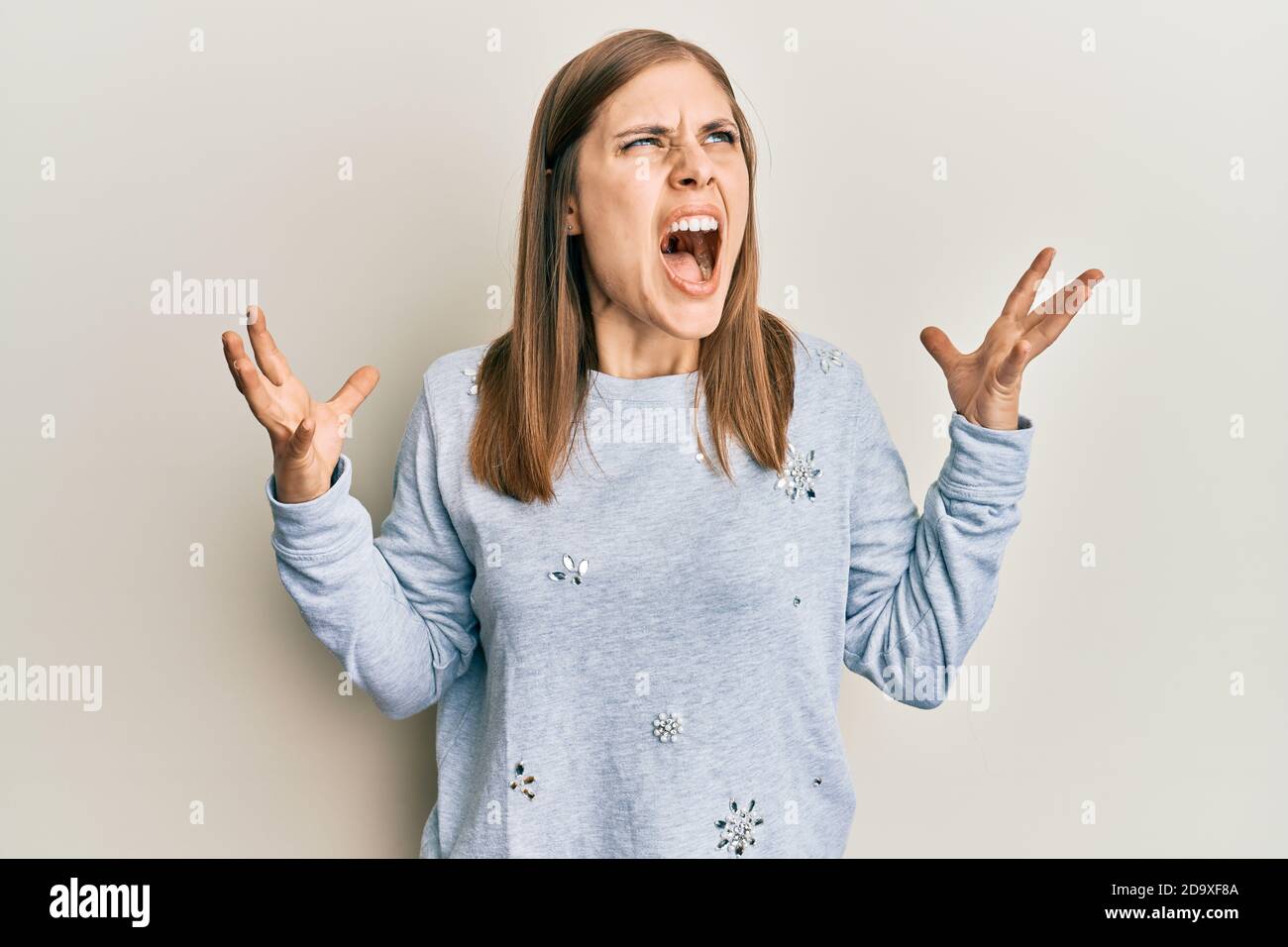 Beautiful caucasian woman wearing casual clothes crazy and mad shouting ...