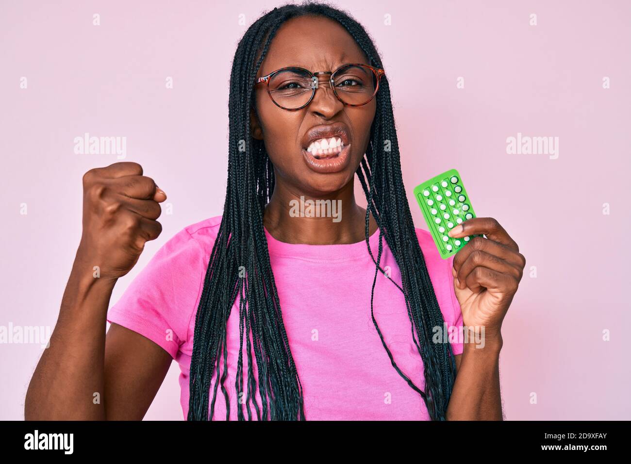 African american woman with braids holding birth control pills annoyed ...