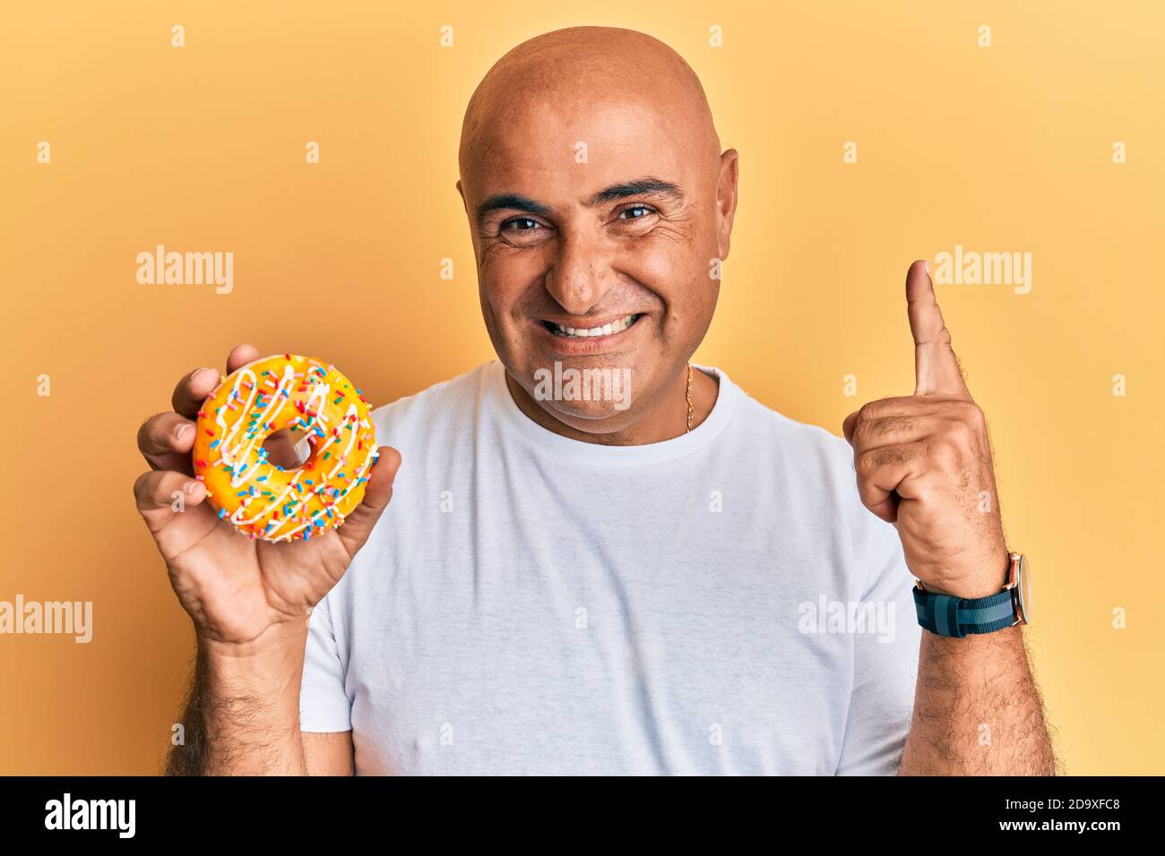 Mature middle east man holding tasty colorful doughnut smiling with an ...