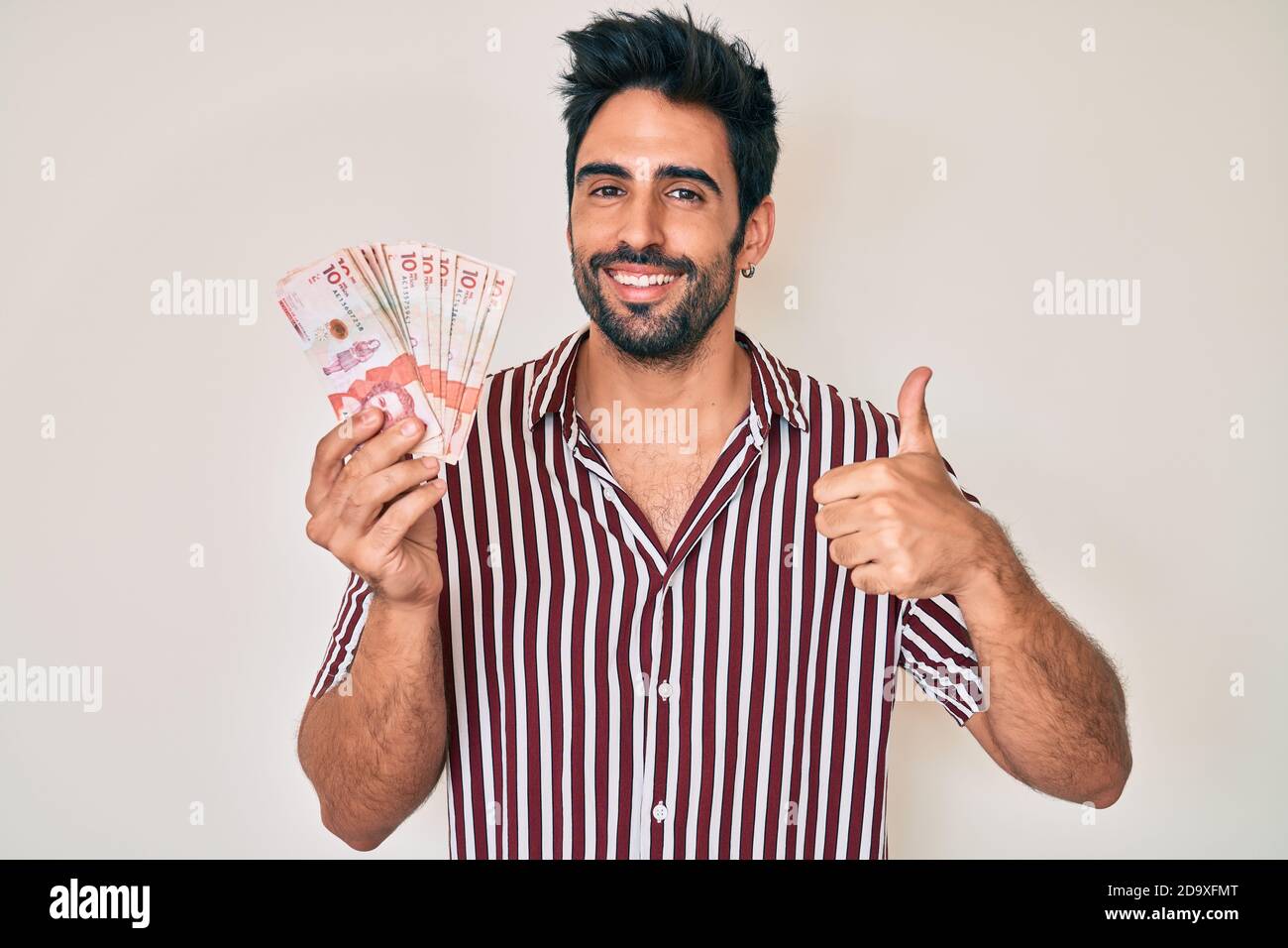 Handsome hispanic man with beard holding colombian pesos smiling happy ...