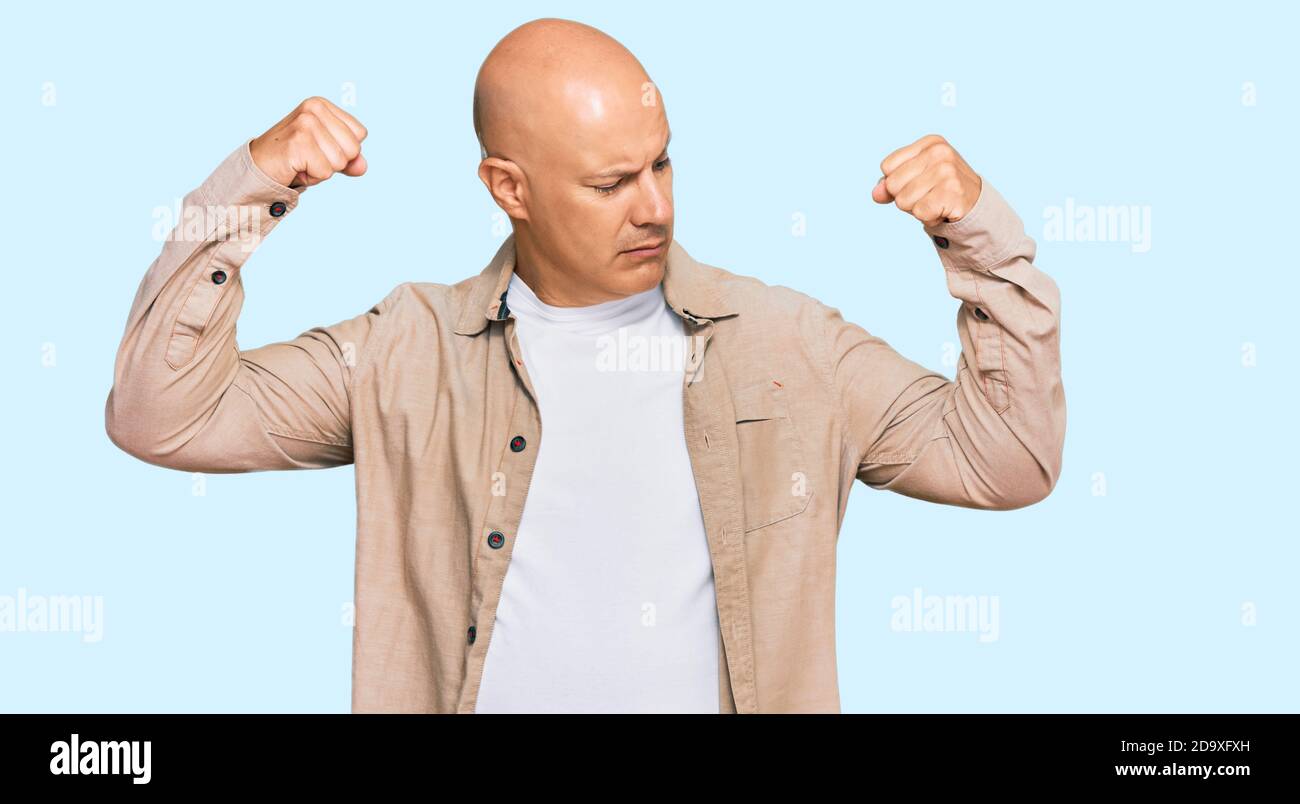 Middle age bald man wearing casual clothes showing arms muscles smiling ...