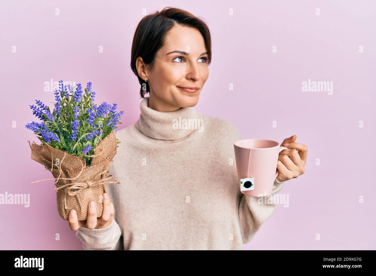 Young brunette woman with short hair drinking a cup of infused lavender ...