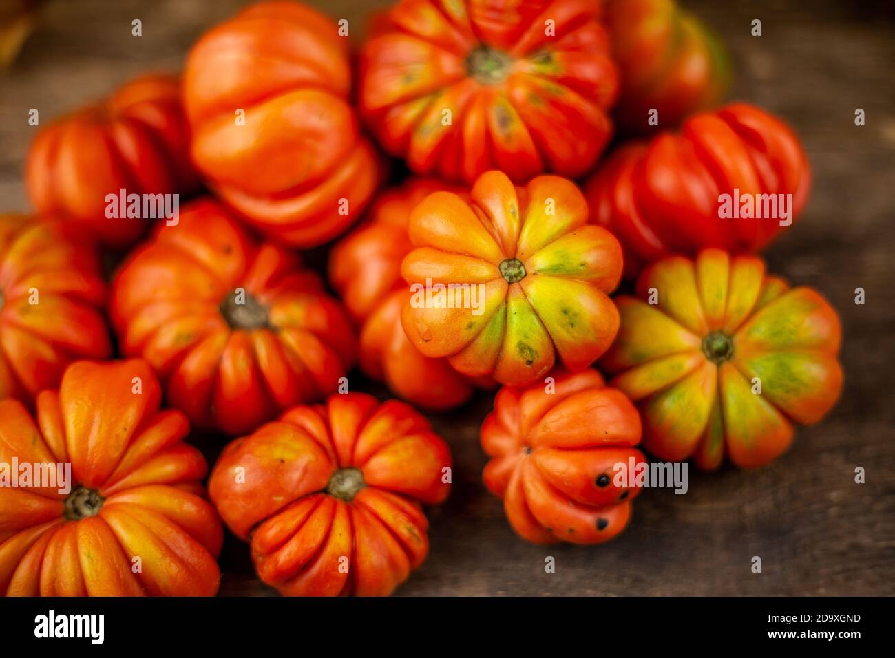 Red ribbed tomatoes on a wooden background. American or Florentine ...