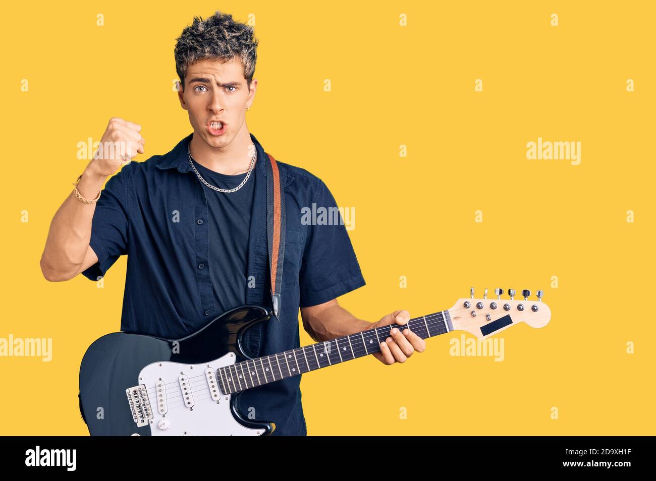 Young handsome man playing electric guitar annoyed and frustrated ...