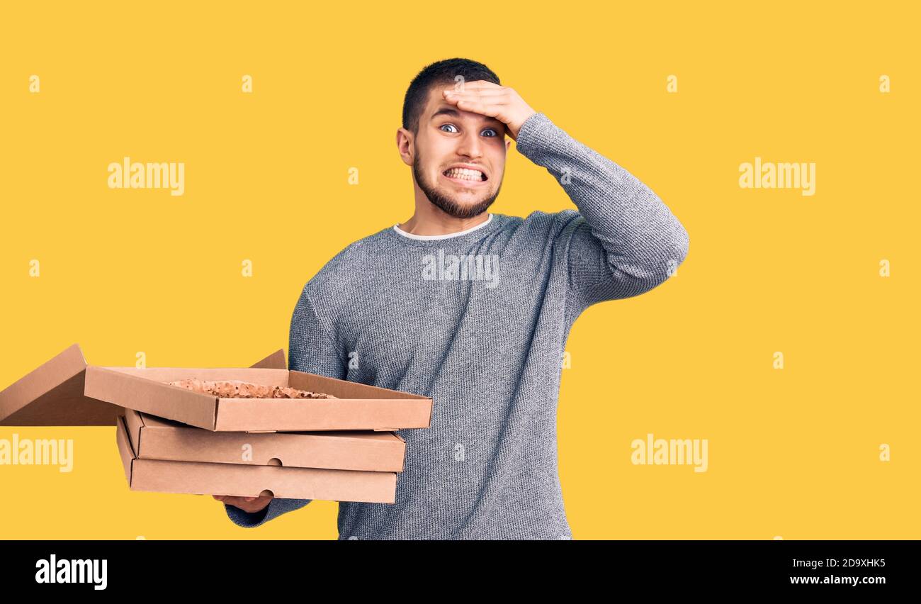 Young handsome man holding delivery italian pizza boxes stressed and ...
