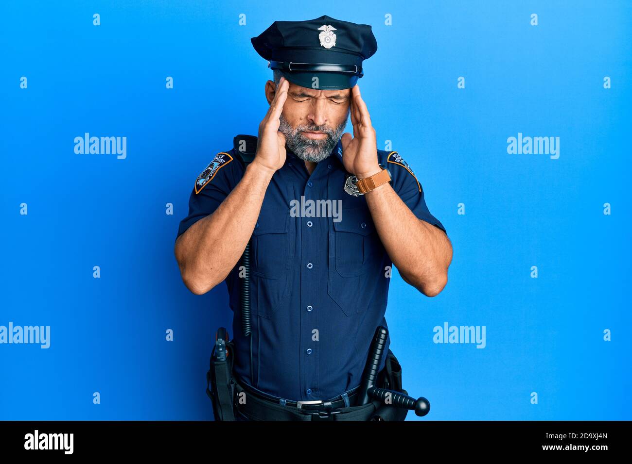 Middle age handsome man wearing police uniform with hand on head ...