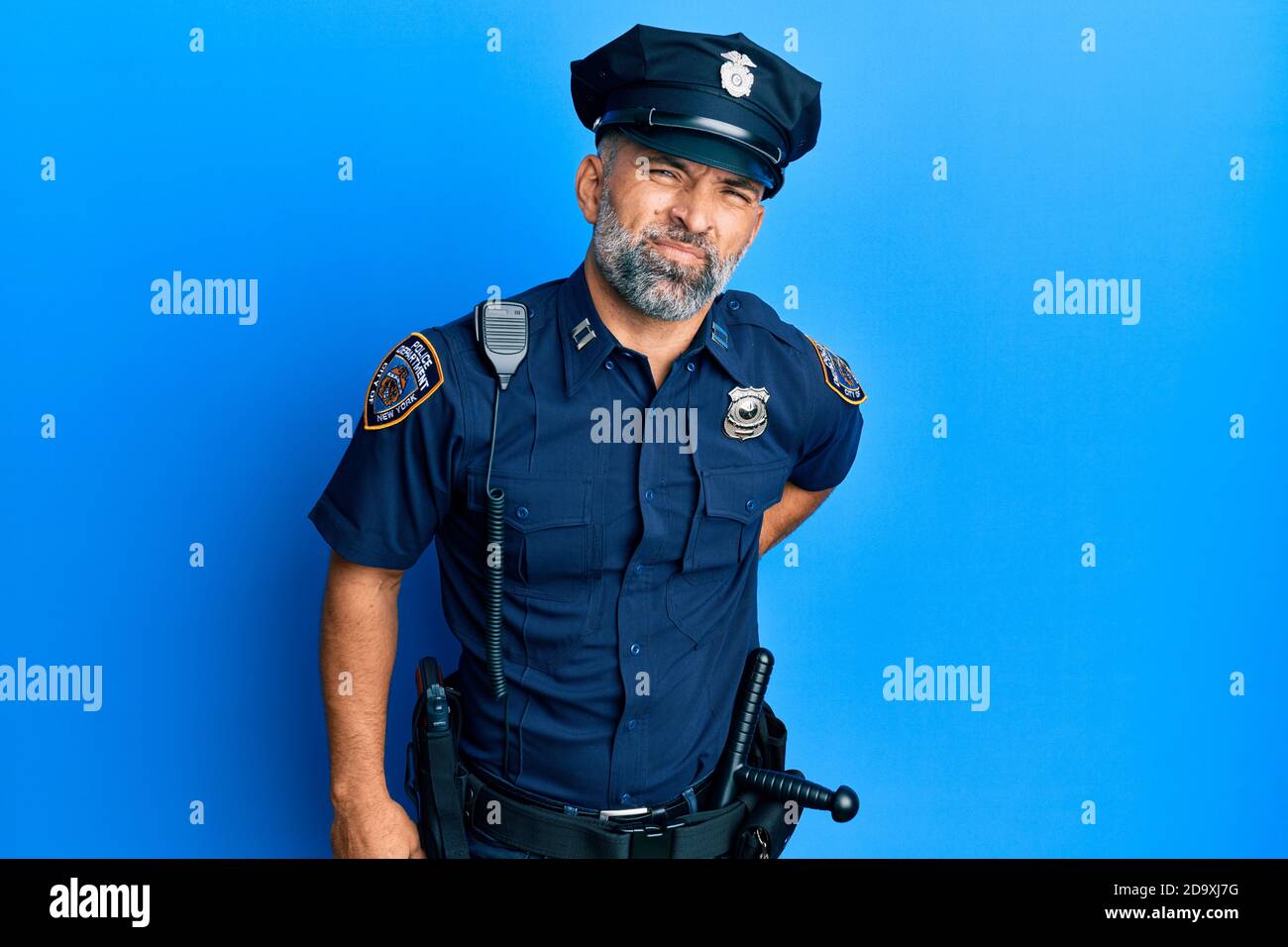 Middle age handsome man wearing police uniform suffering of backache ...