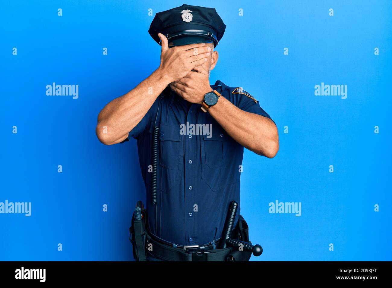 Middle age handsome man wearing police uniform covering eyes and mouth ...