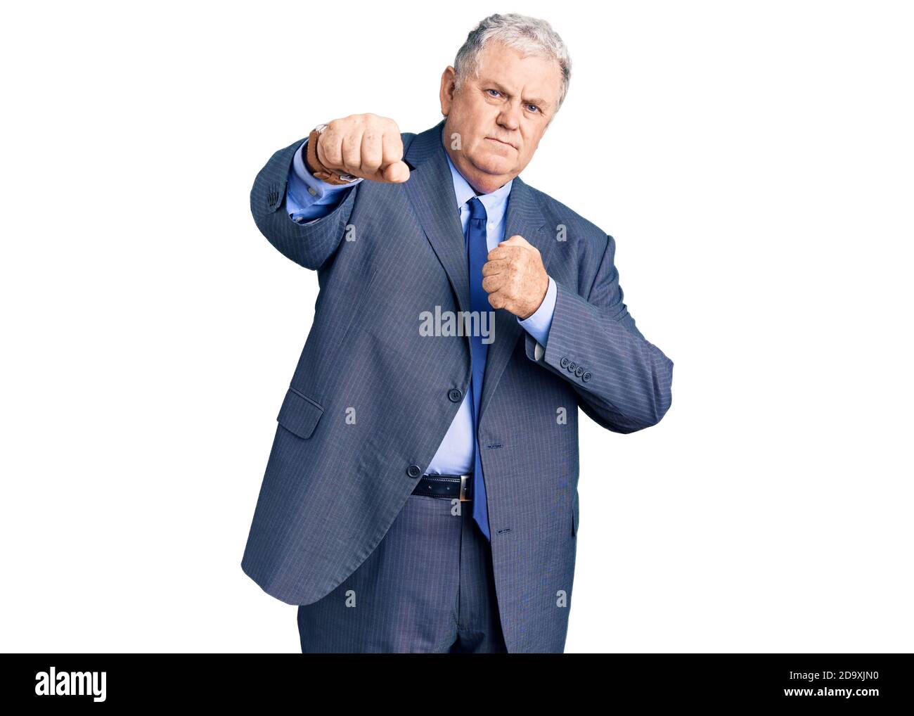 Senior grey-haired man wearing business jacket punching fist to fight ...