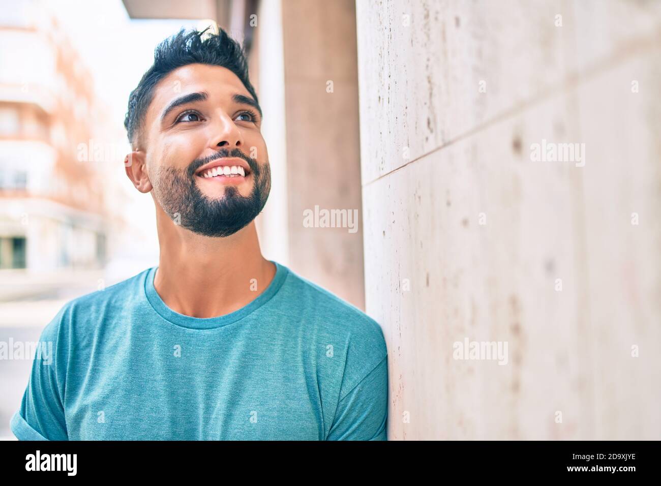 Young arab man smiling happy leaning on the wall at the city Stock ...