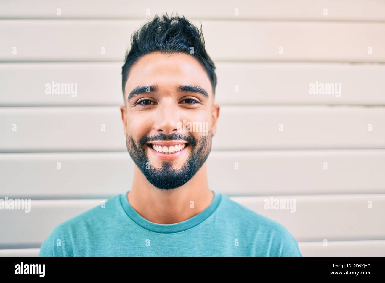 Young arab man smiling happy leaning on the wall at the city Stock ...