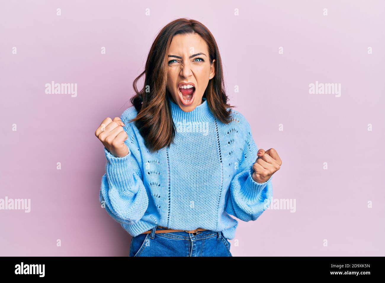 Young brunette woman wearing casual winter sweater over pink background ...