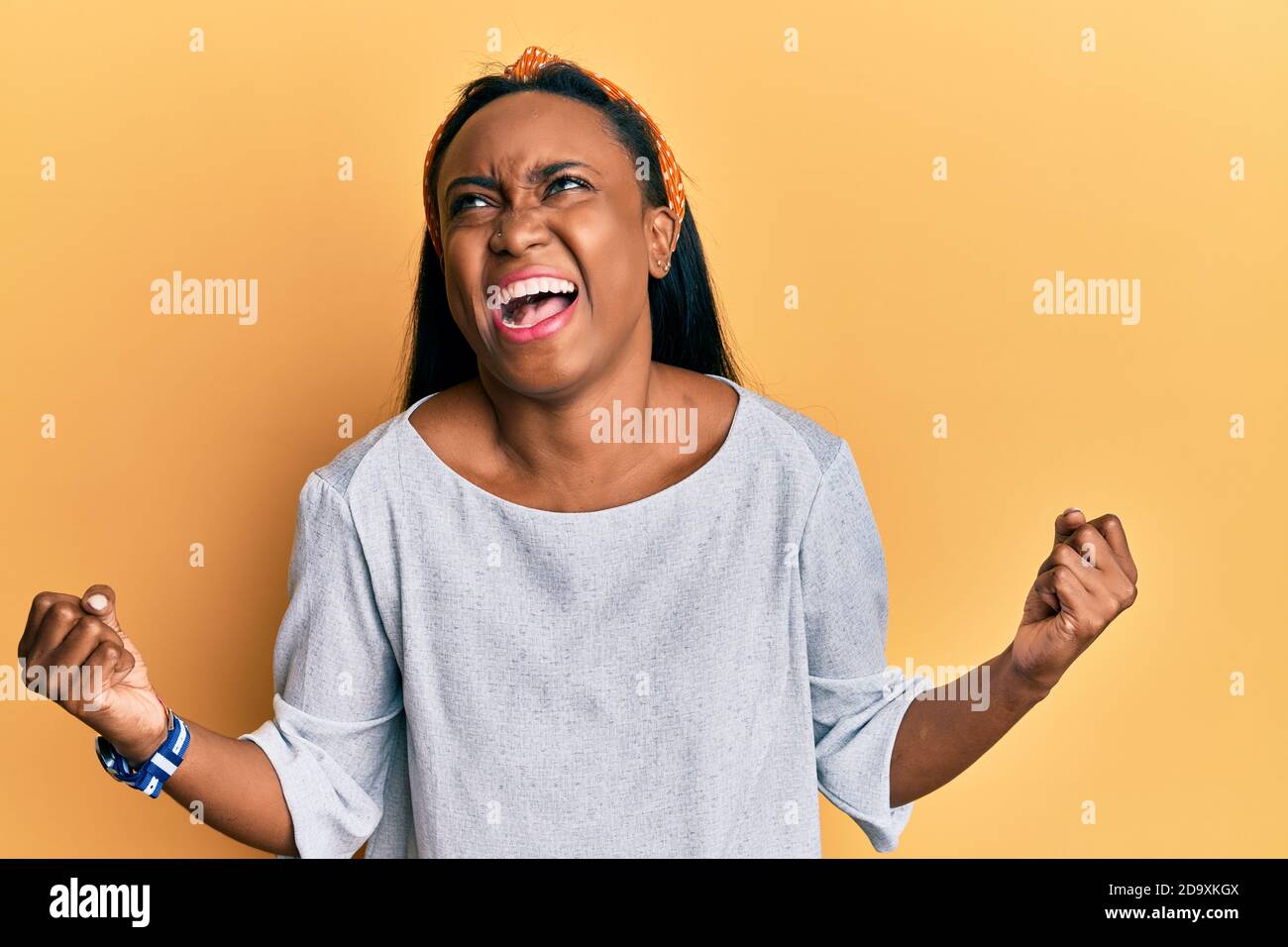 Young african woman wearing casual clothes over yellow background crazy ...