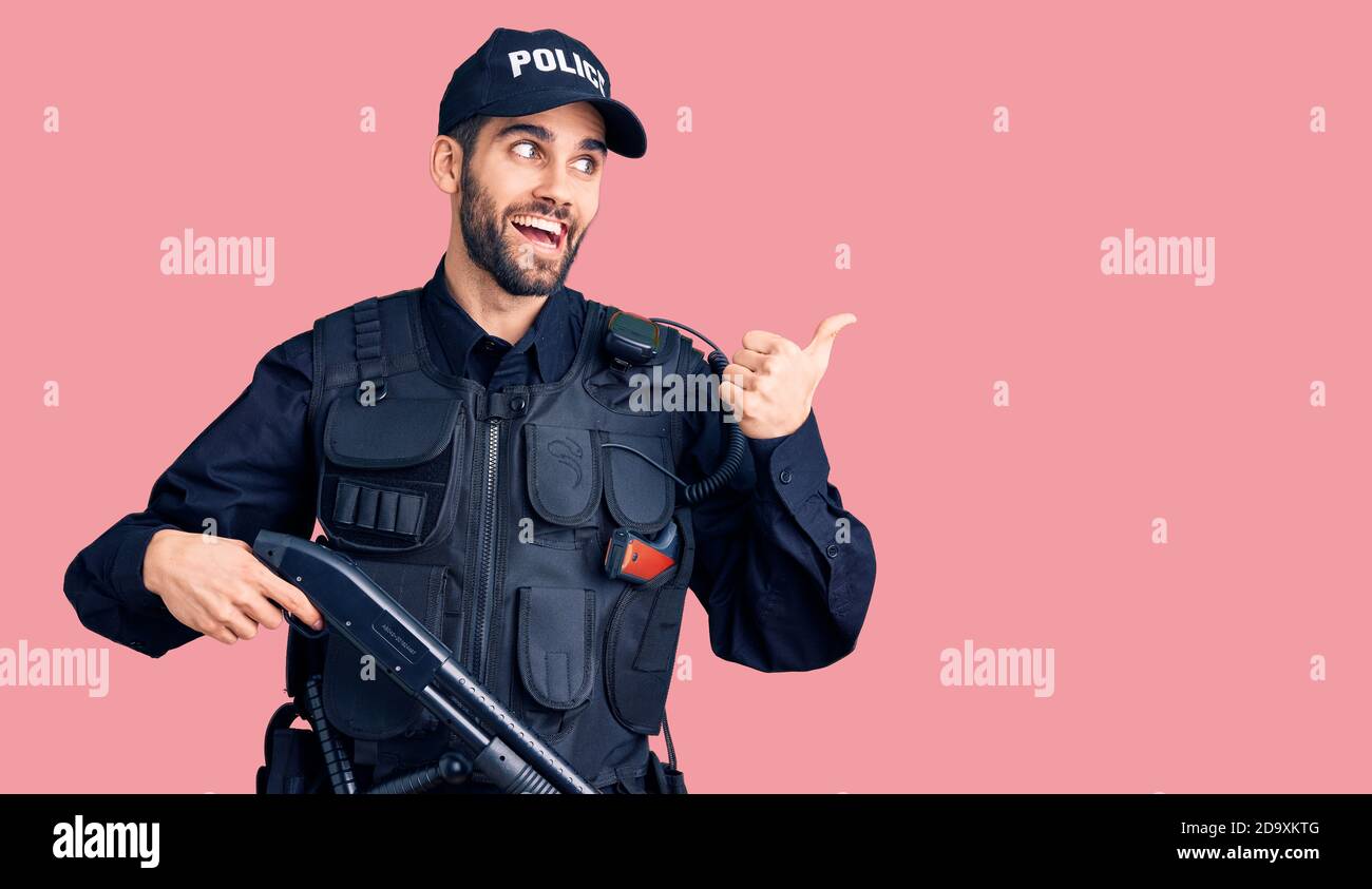 Young handsome man with beard wearing police uniform holding shotgun ...