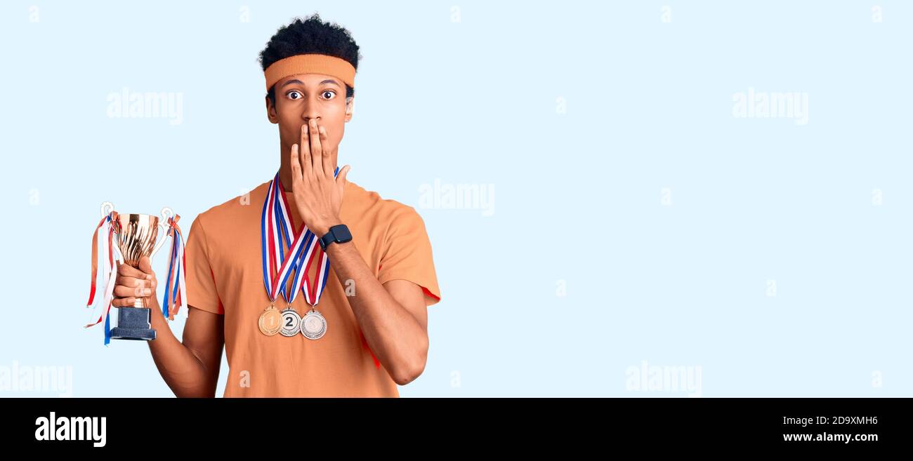 Young african american man holding champion trophy wearing medals ...