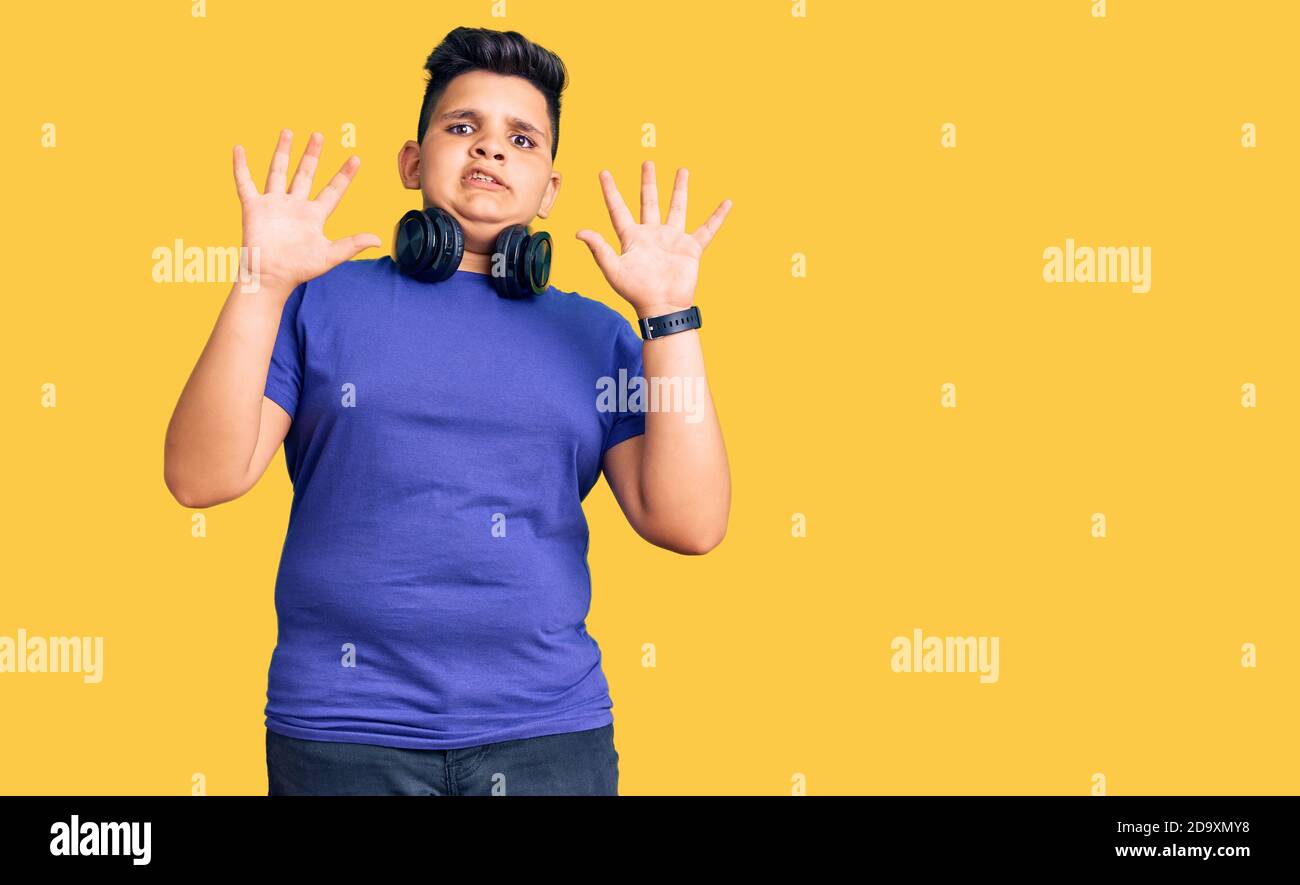 Little boy kid listening to music wearing headphones afraid and ...