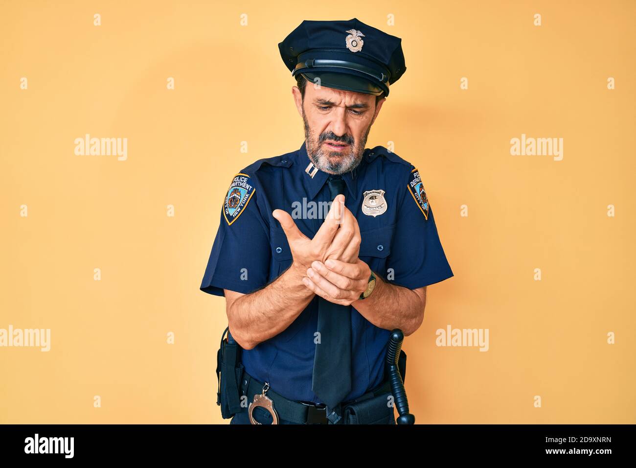 Middle age hispanic man wearing police uniform suffering pain on hands ...