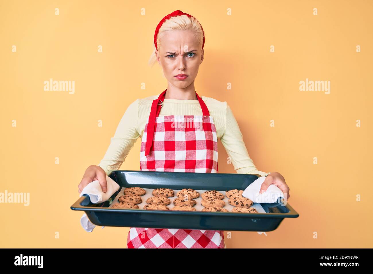 Young blonde woman wearing baker uniform holding homemade cookies ...