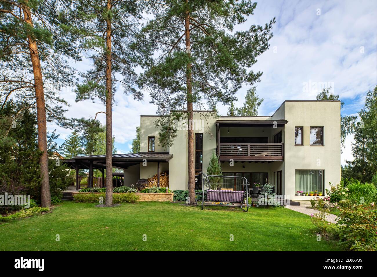 Modern exterior of luxury cottage with wooden terrace. Swing in garden ...