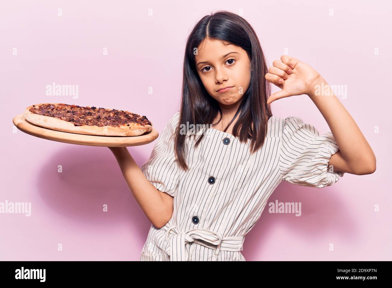 Beautiful child girl holding italian pizza with angry face, negative ...
