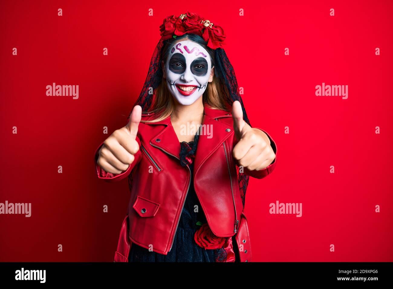Woman wearing day of the dead costume over red approving doing positive ...