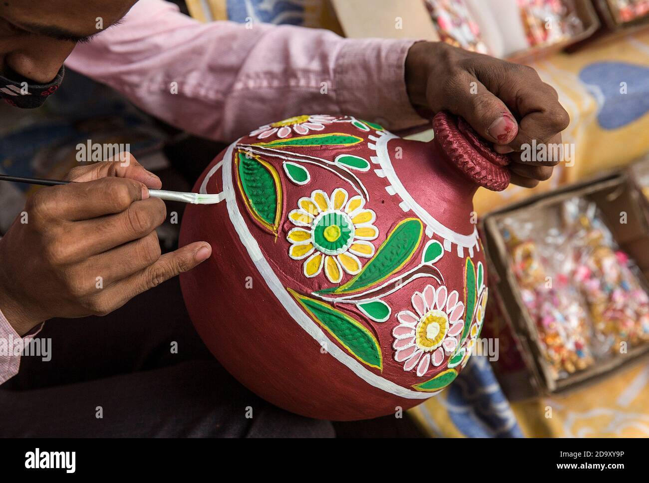 New Delhi, India. 8th Nov, 2020. An Indian potter colors an earthen pot ...