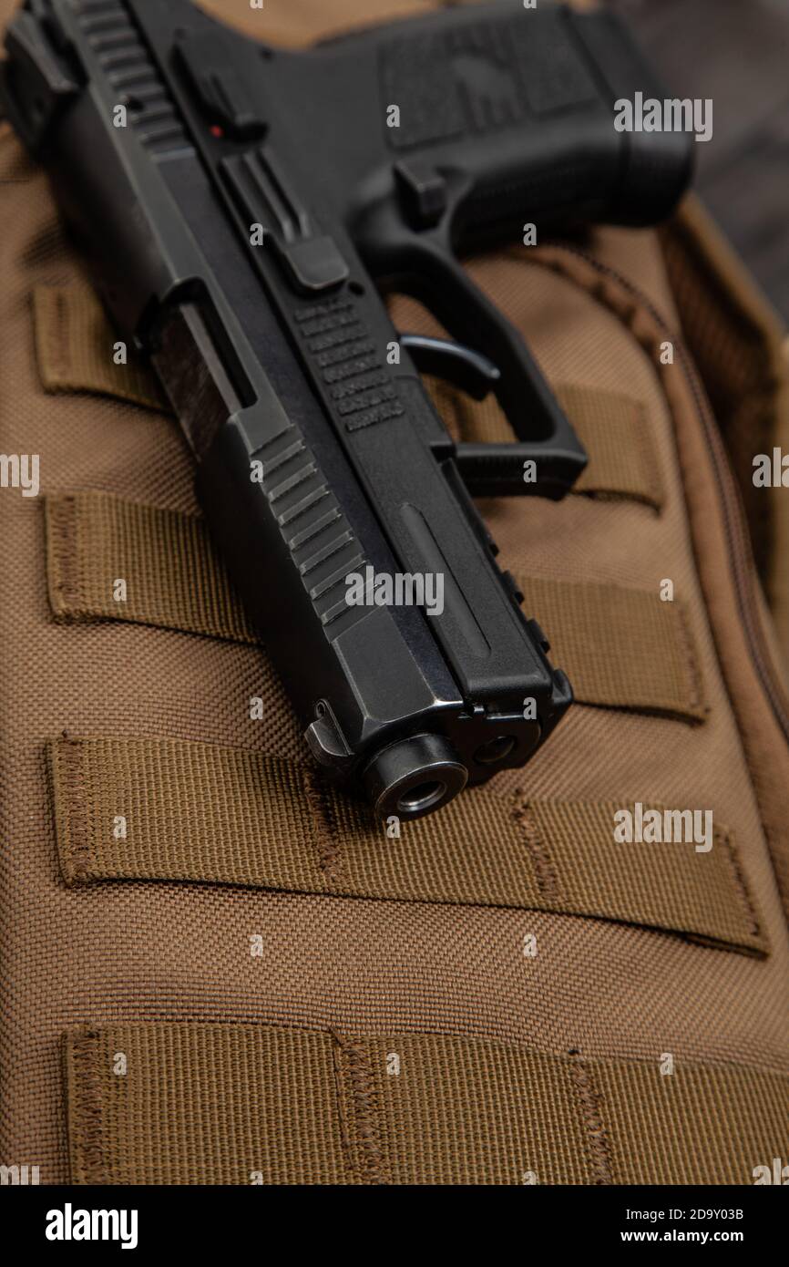 A modern black pistol on a brown military backpack. Weapons for defense ...