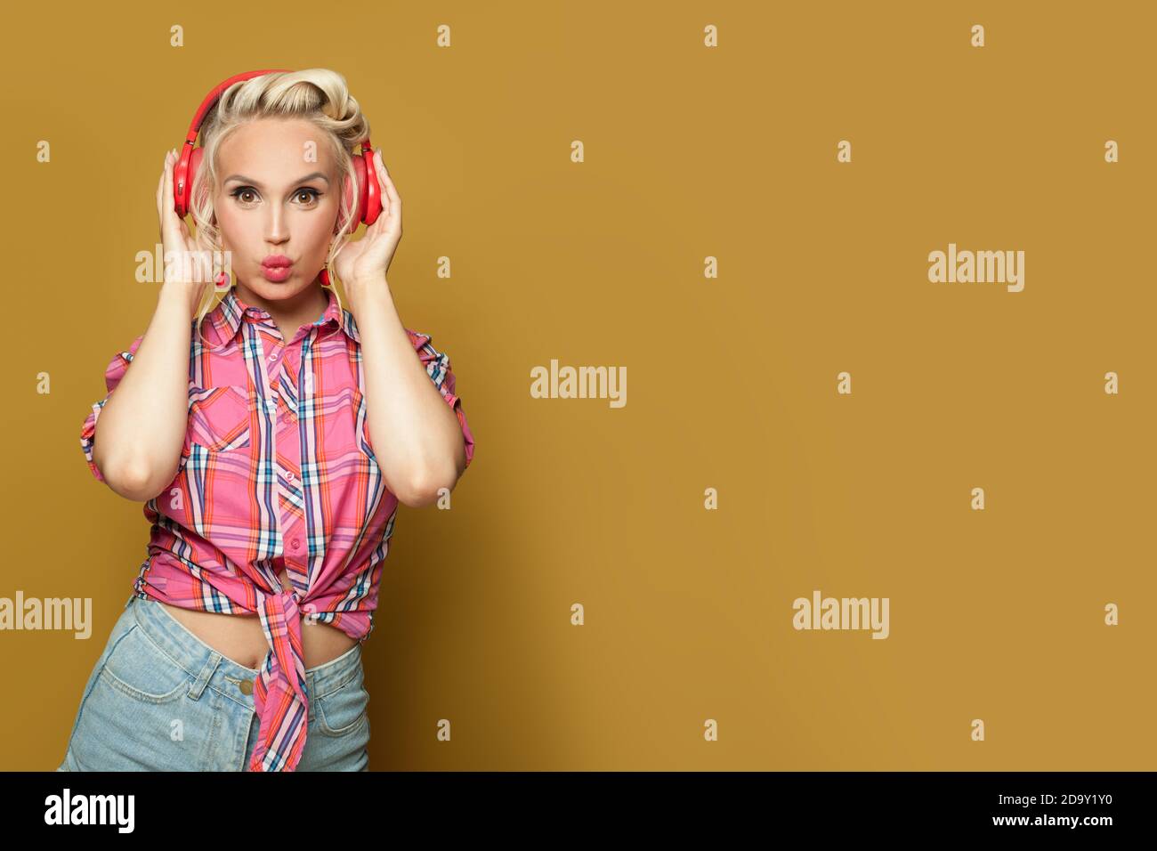 Perfect pinup woman with headphones enjoying music on bright yellow ...