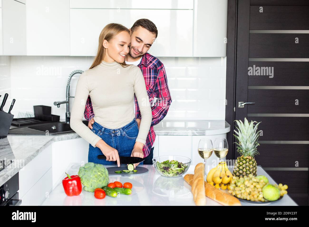 Picture of young couple in the kitchen hugging while cooking Stock ...