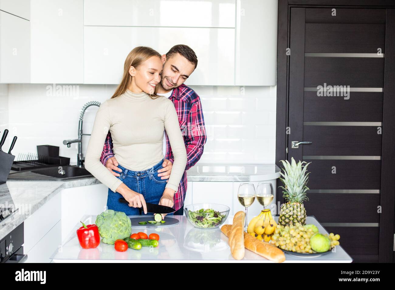Picture of young couple in the kitchen hugging while cooking Stock ...