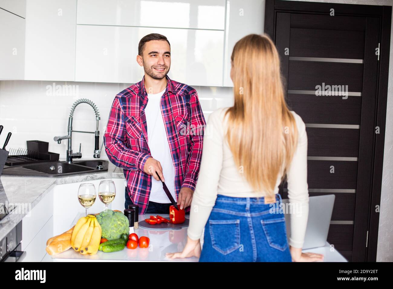Beautiful couple is talking and smiling while cooking healthy food in ...