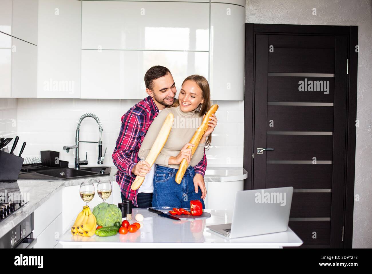 Attractive couple having fun in the kitchen fencing with ladle and ...