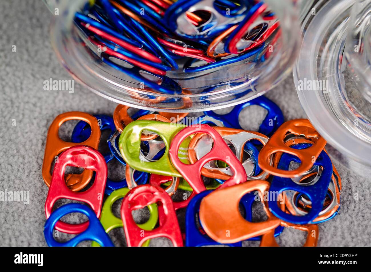 a top down close up view of a jar of multi colored can pull tabs laying ...