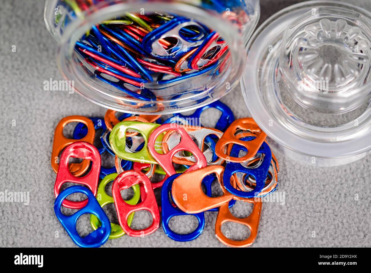 a top down wide view of a jar of multi colored can pull tabs laying on ...