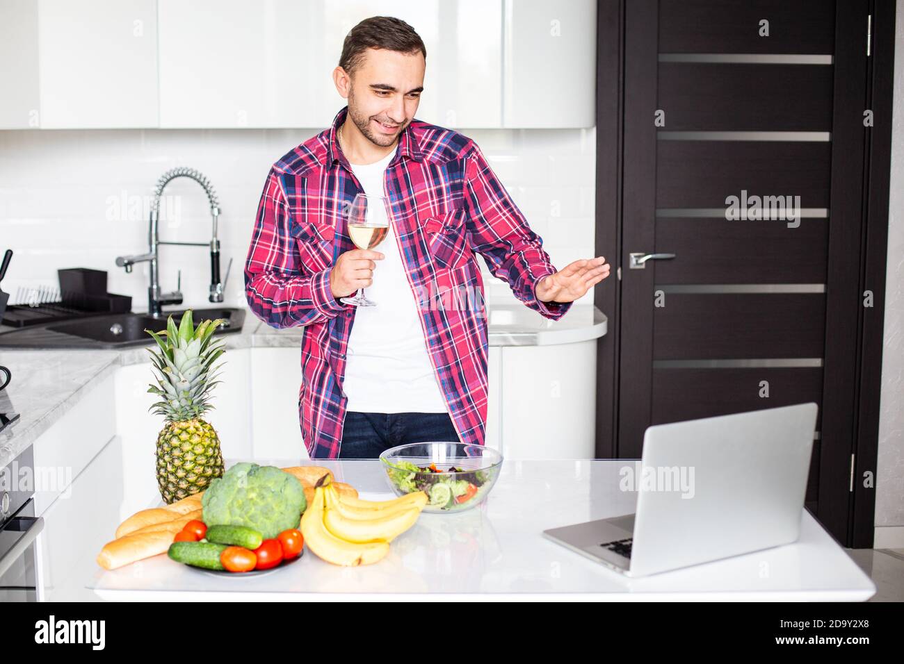 Portrait of handsome man in kitchen. Young man cooking while having ...